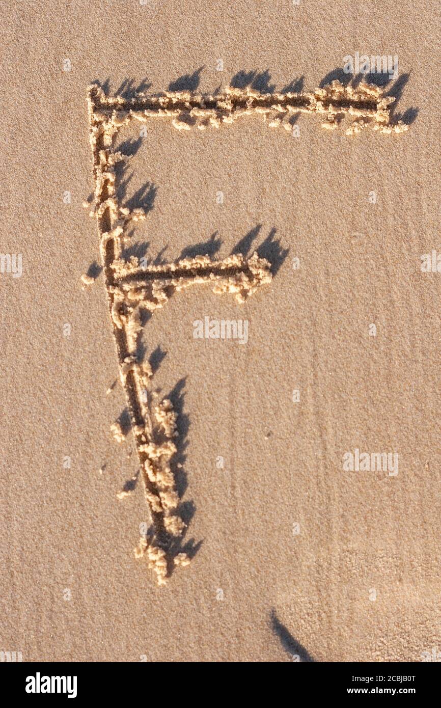F - Alphabet letter written on sand Stock Photo - Alamy