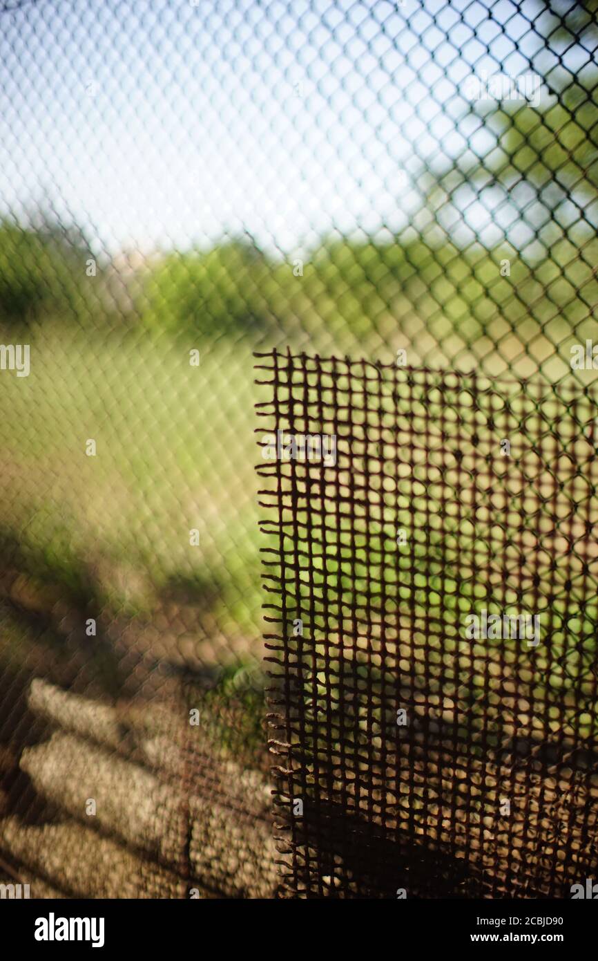 old rusty mesh fence and the same sheet of rust mesh near the summer ...