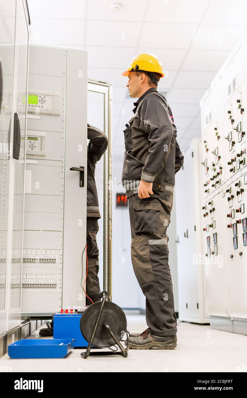 Two field service crew engineers inspect system with relay test set ...