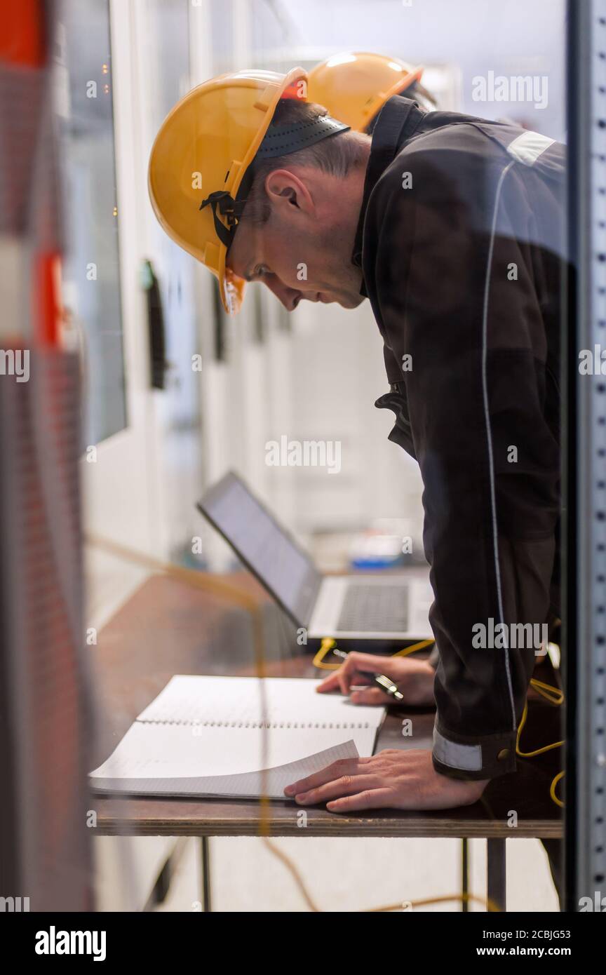 Two maintenance engineers inspect relay protection system with laptop ...