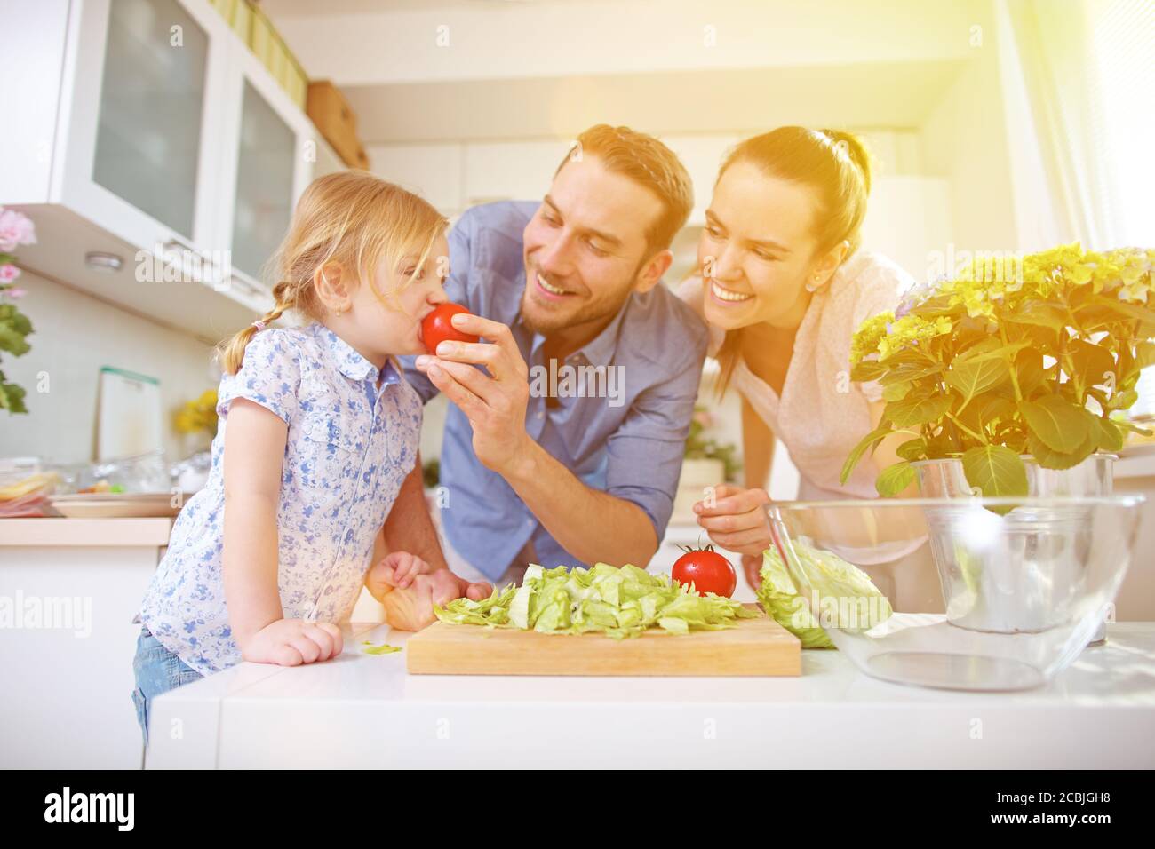 Family with child eats fresh vegetables in the summer in the kitchen ...