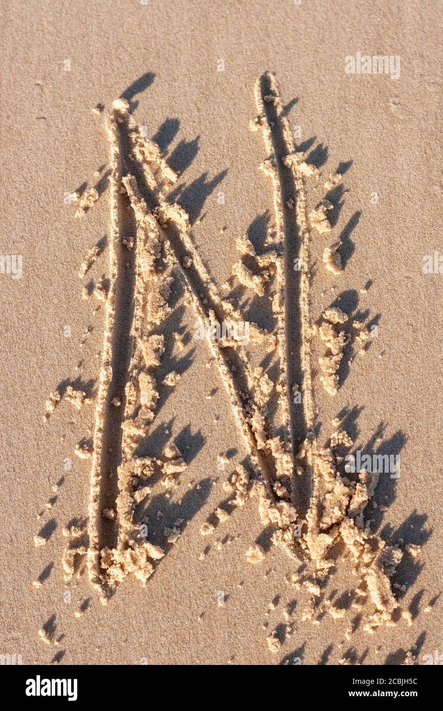 N - Alphabet letter written on sand Stock Photo - Alamy