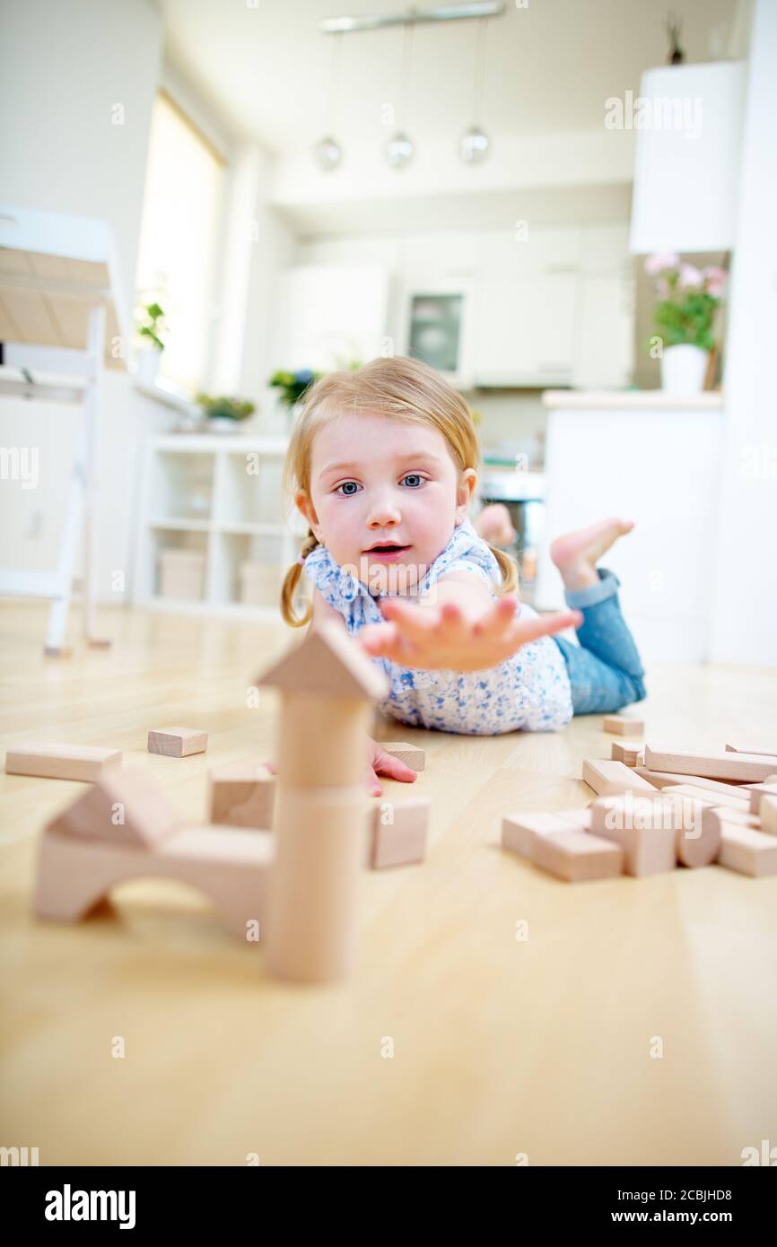 Toddler reaches for wooden building blocks on the floor Stock Photo - Alamy