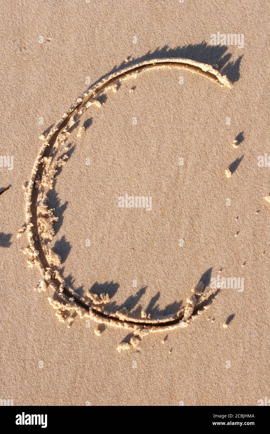 C - Alphabet letter written on sand Stock Photo - Alamy