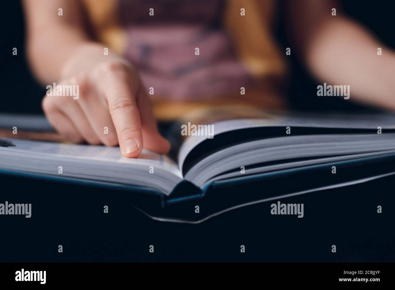 Reading open book following text with finger Stock Photo - Alamy