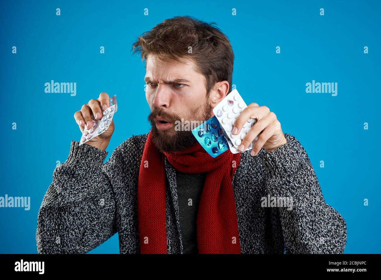 Man with pills on a blue background health medicine and warm clothes ...