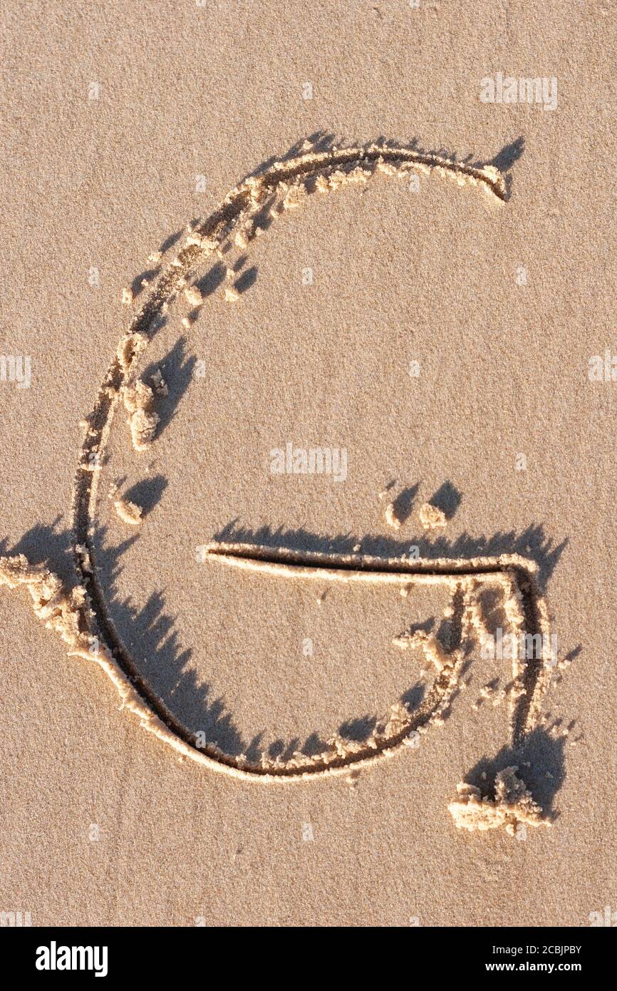 G - Alphabet letter written on sand Stock Photo - Alamy