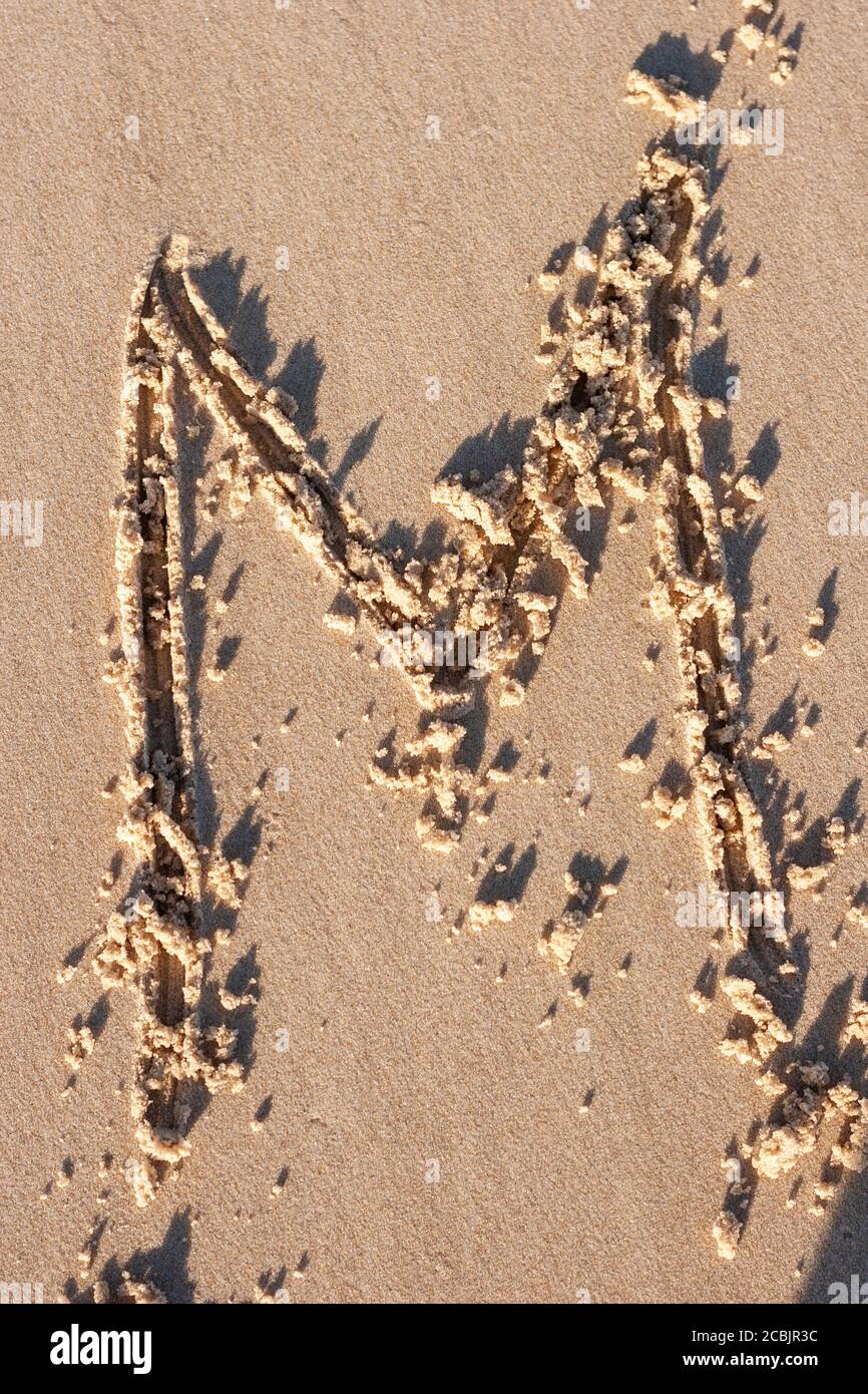 M - Alphabet letter written on sand Stock Photo - Alamy