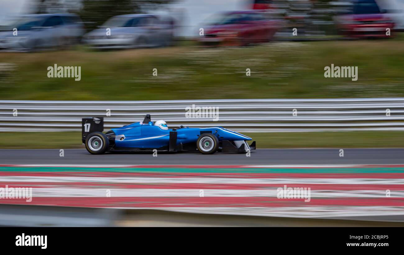 A panning shot of a blue racing car as it circuits a track Stock Photo ...