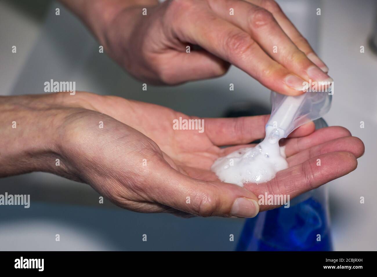 A close up of a person using a soap dispenser Stock Photo - Alamy