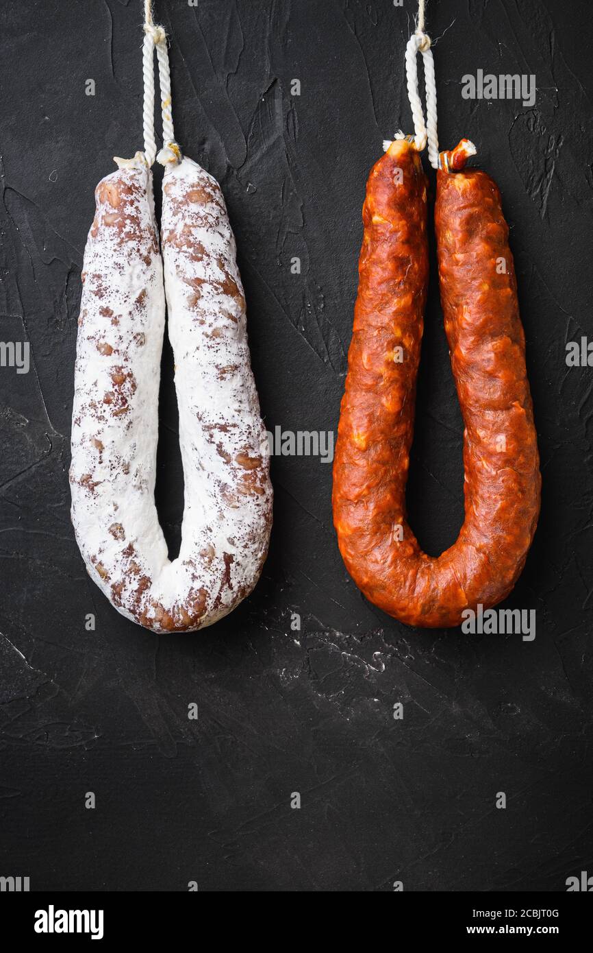 Spanish salami, fuet and chorizo sausages hang from a rack on black ...
