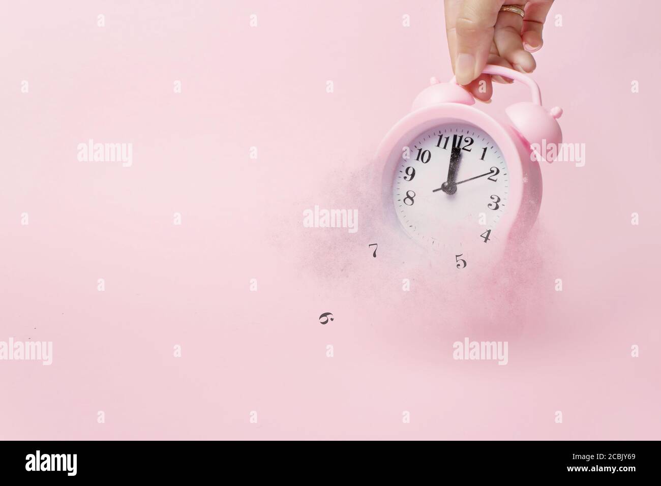A hand holds alarm clock break down and dispersion to particle. A ...