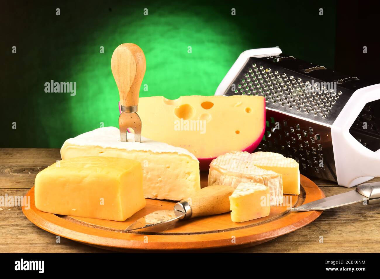 Bottle and glass of wine with an assorted table of cheese and a barrel ...