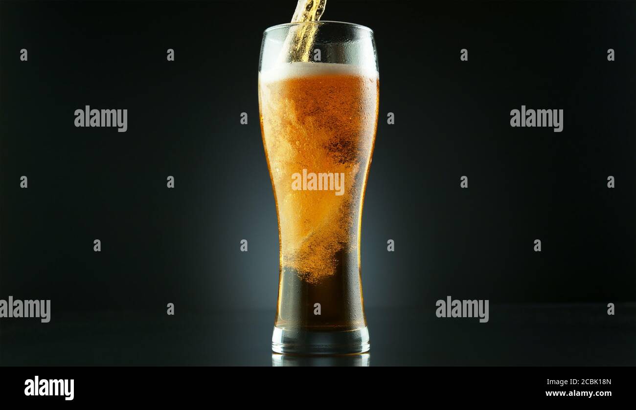 Freeze motion of pouring beer into glass pint, isolated on black ...