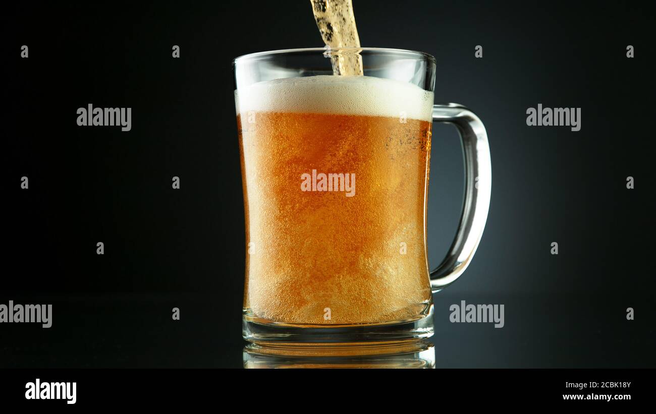 Freeze motion of pouring beer into glass pint, isolated on black ...