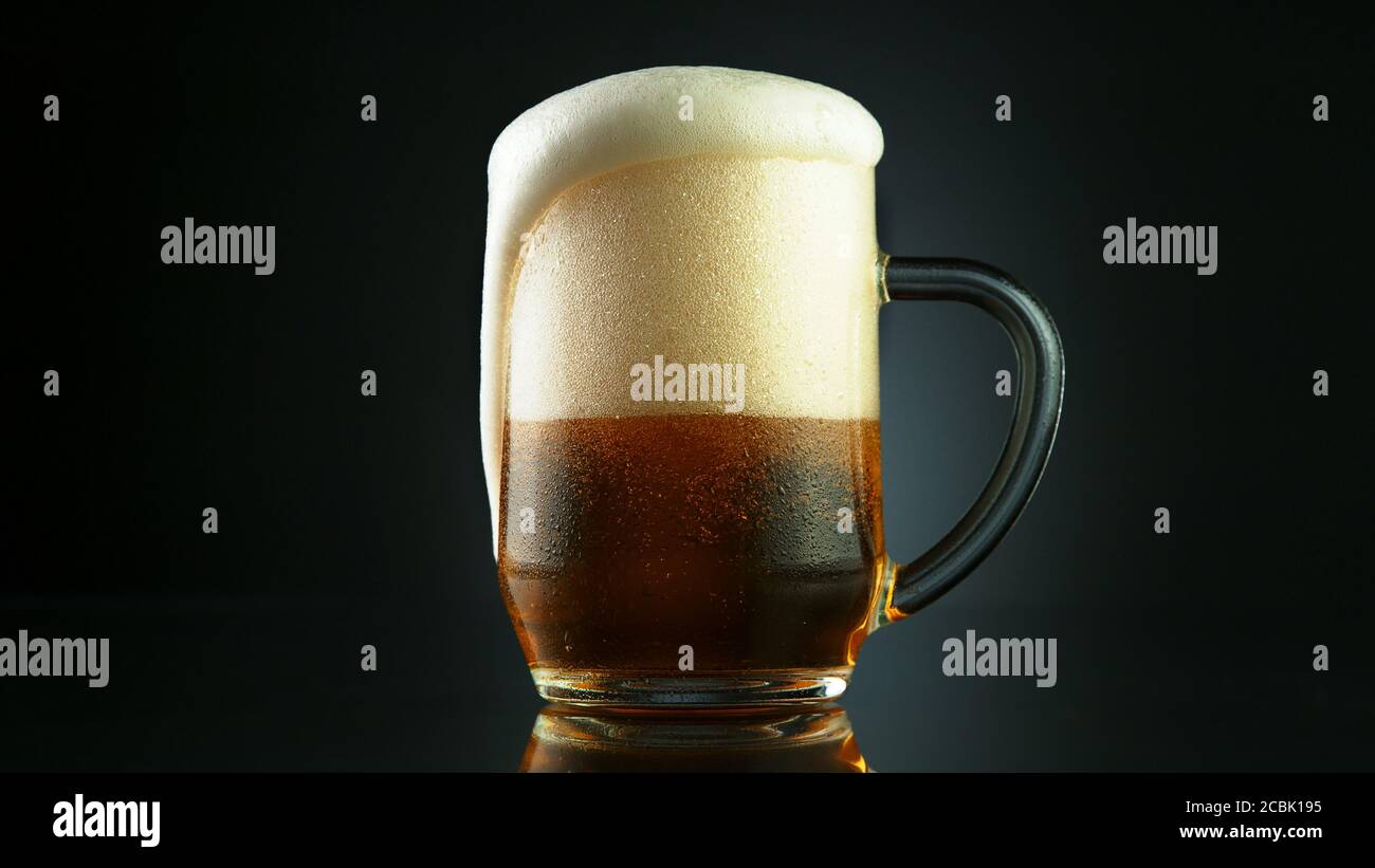 Beer foam overflowing from glass pint, isolated on black background ...