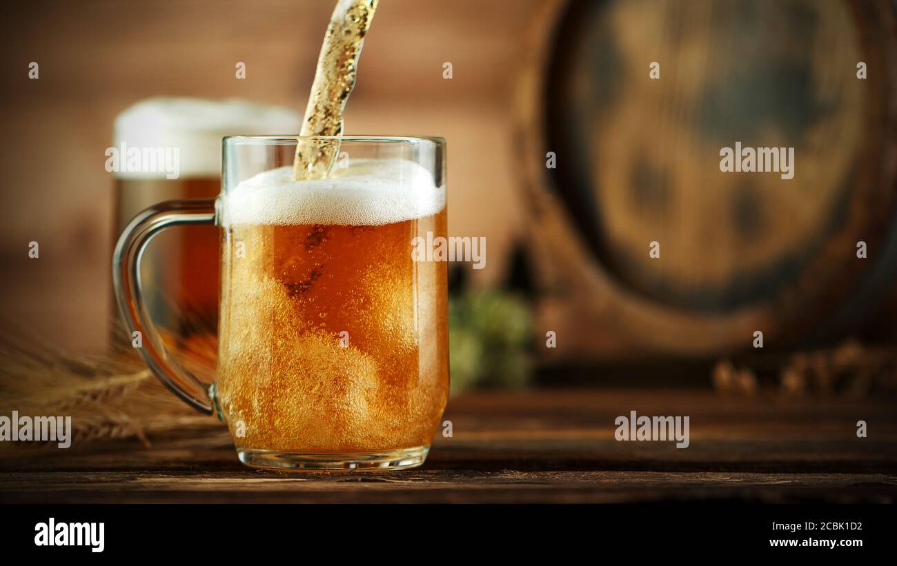 Pouring beer into glass pint, placed on wooden table with keg Stock ...