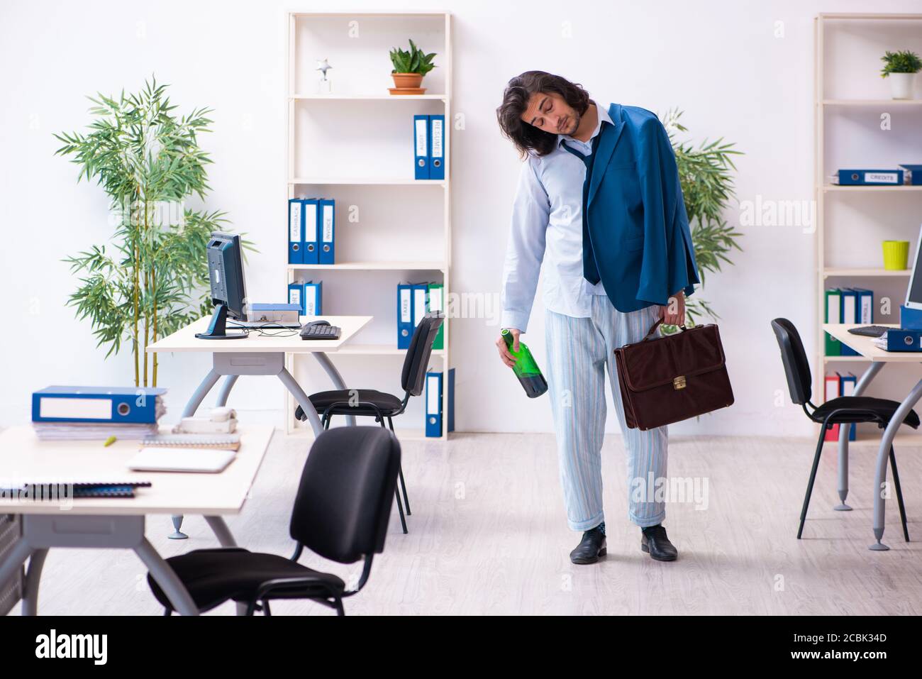 Male employee coming to work after the party Stock Photo - Alamy