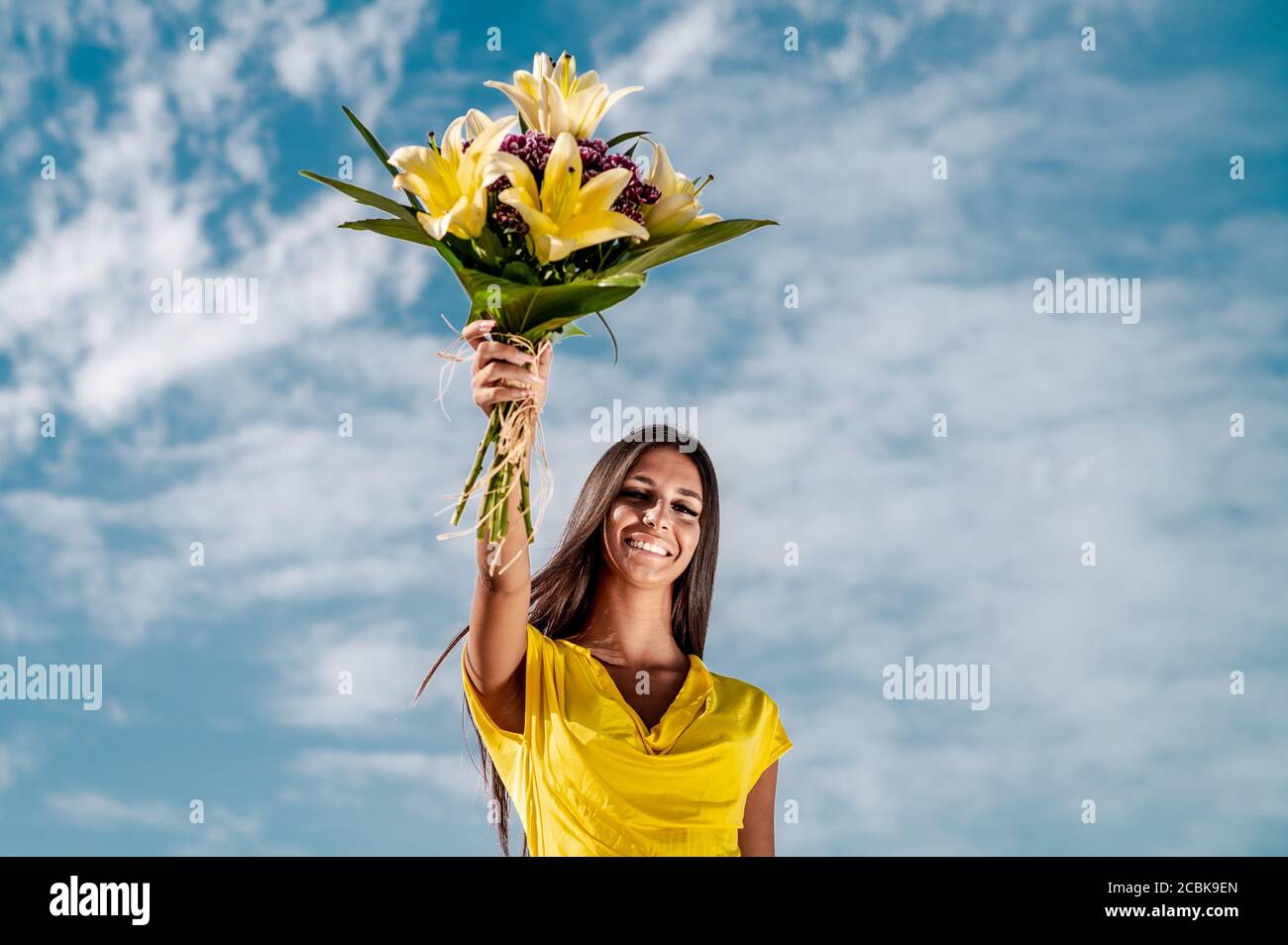 A low angle shallow focus shot of a female holding a bouquet of flowers ...