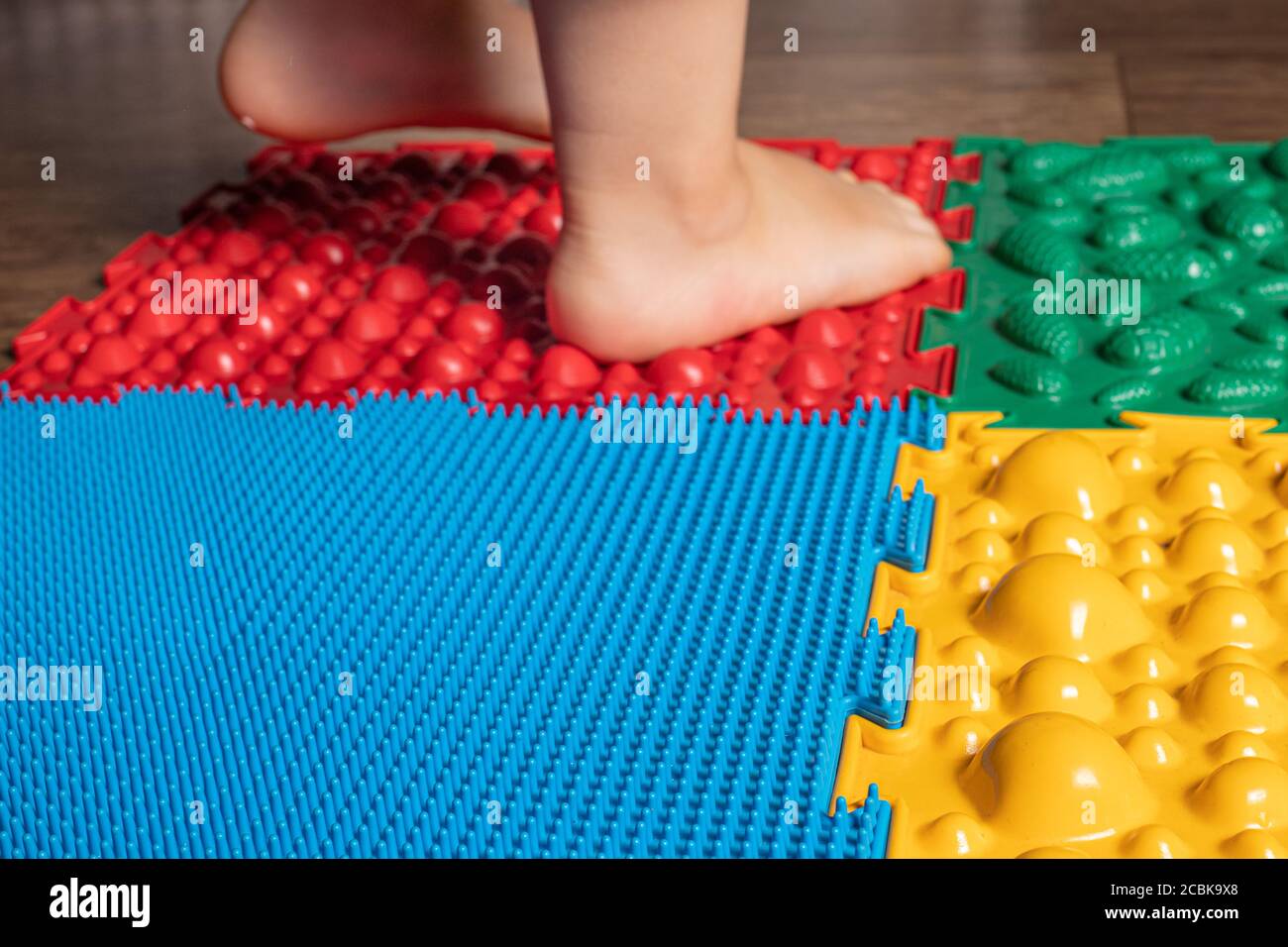 The legs of a small child on orthopedic mats. Bright surfaces for ...