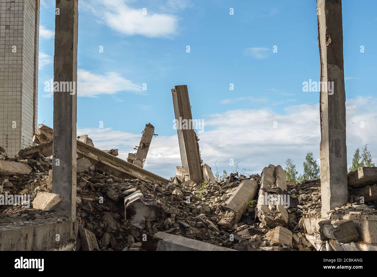Concrete fragments of a destroyed building against the blue sky ...