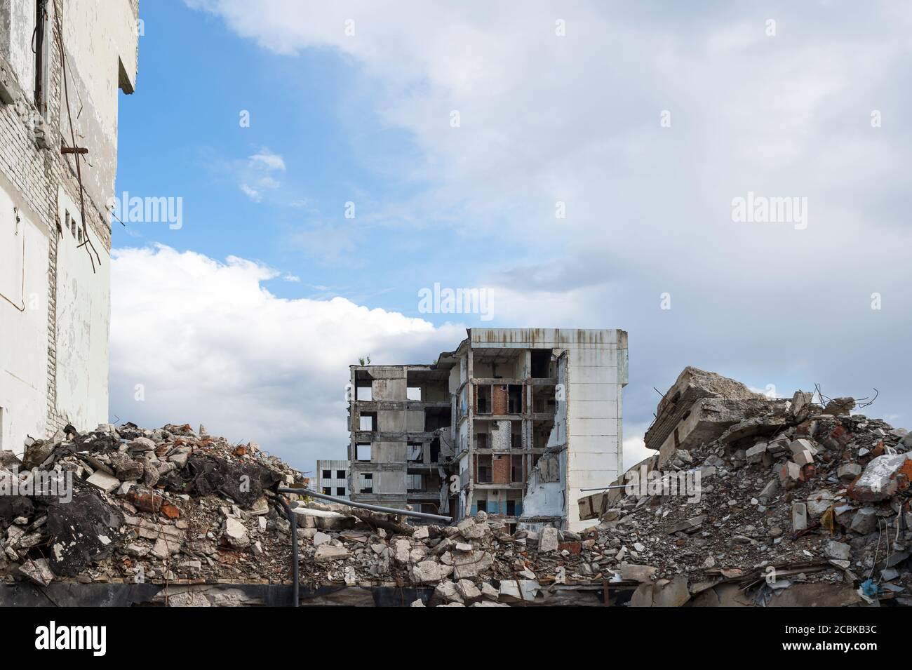 Concrete debris with rebar and a collapsed wall in the foreground ...