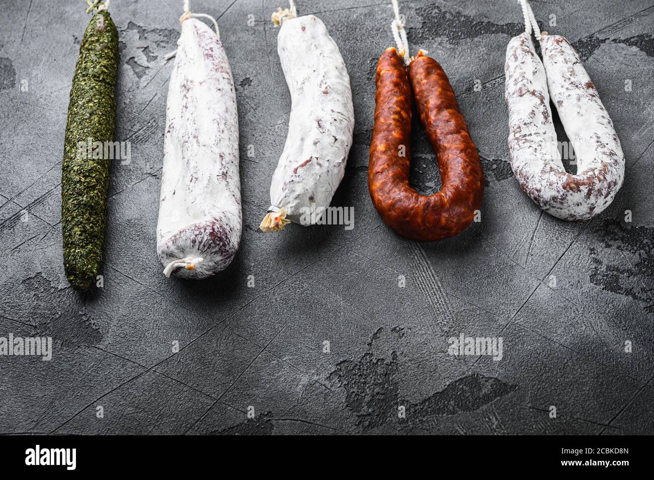Spanish dry salami from a rack at market on grey background with space ...