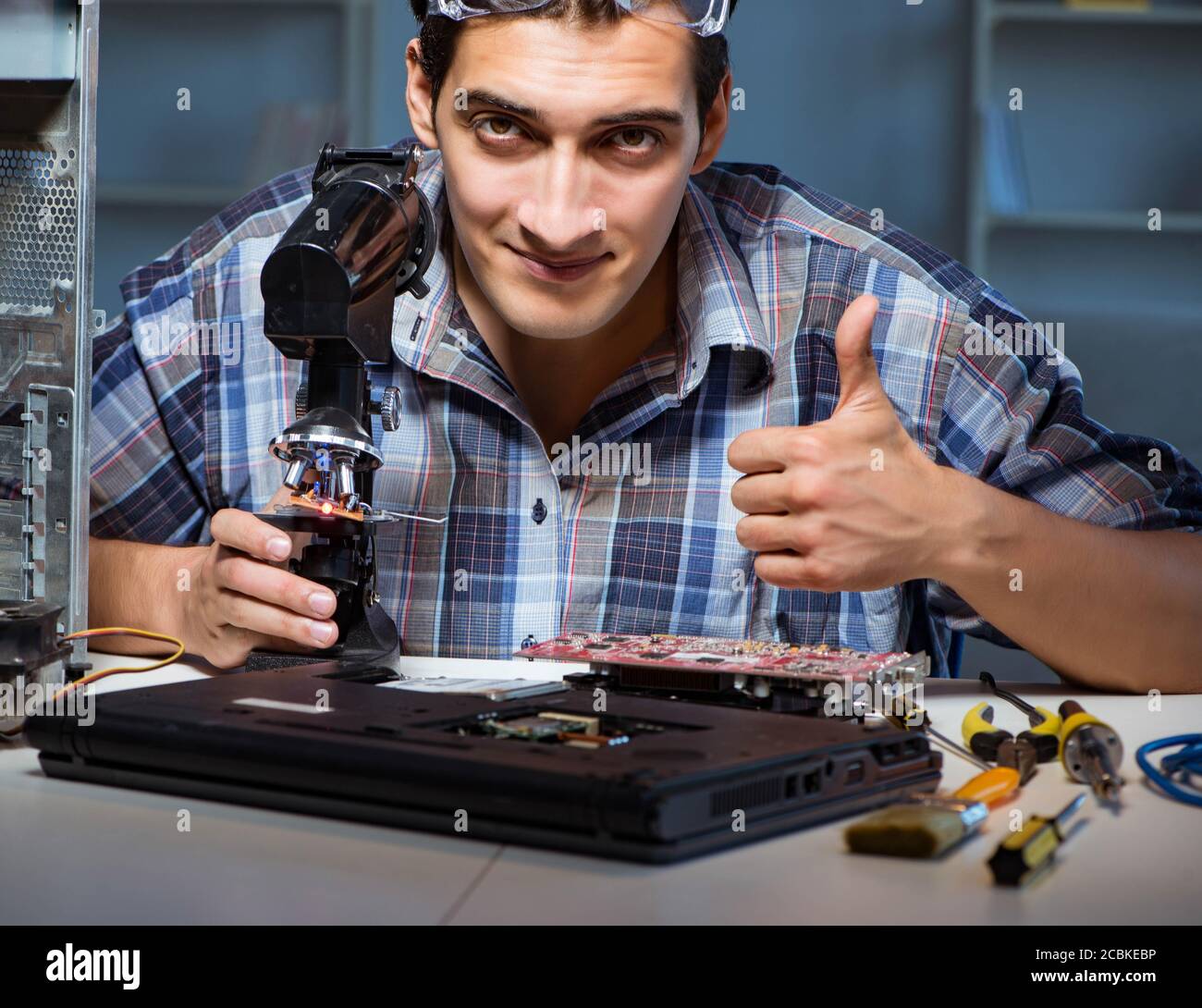 The repairman trying to repair laptop with miscroscope Stock Photo - Alamy