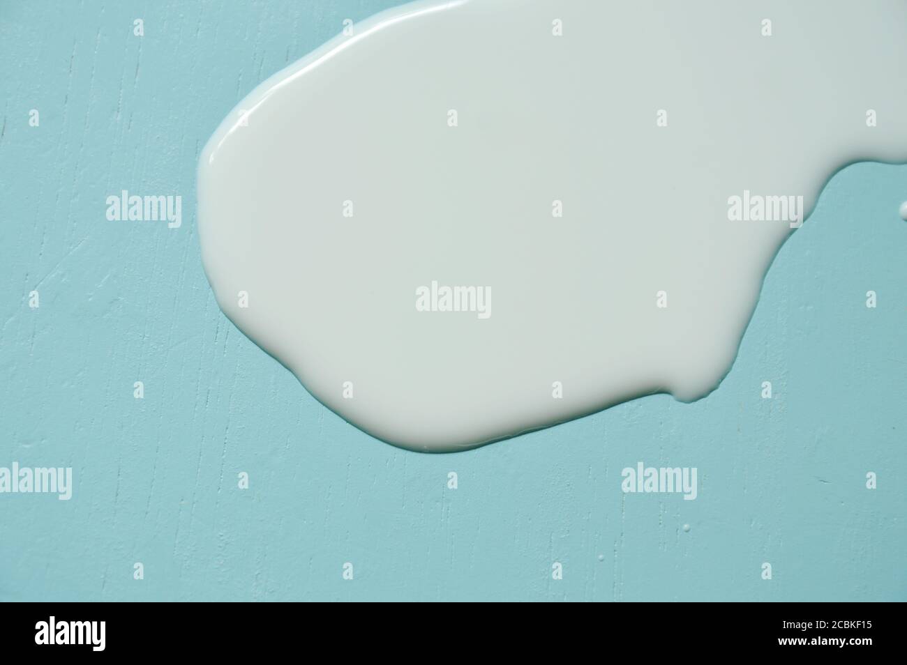 fresh white milk splatter on blue table background Stock Photo - Alamy