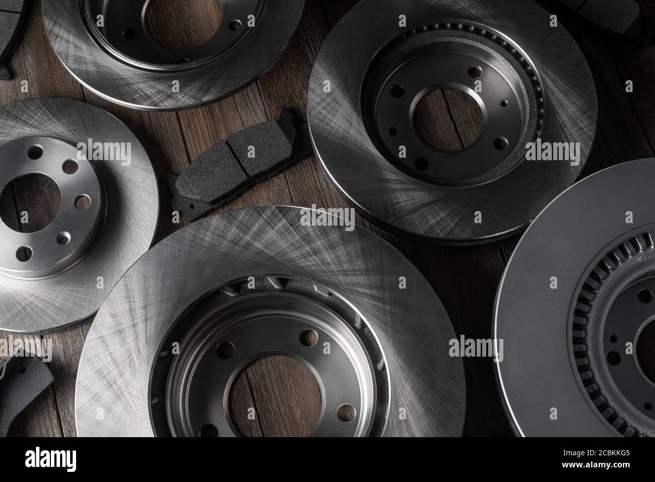 Flat lay shot of brake discs and friction pads on wooden background ...