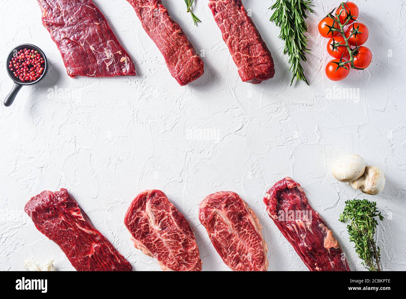 Set of different alternative types of raw beef steaks,on a white stone ...