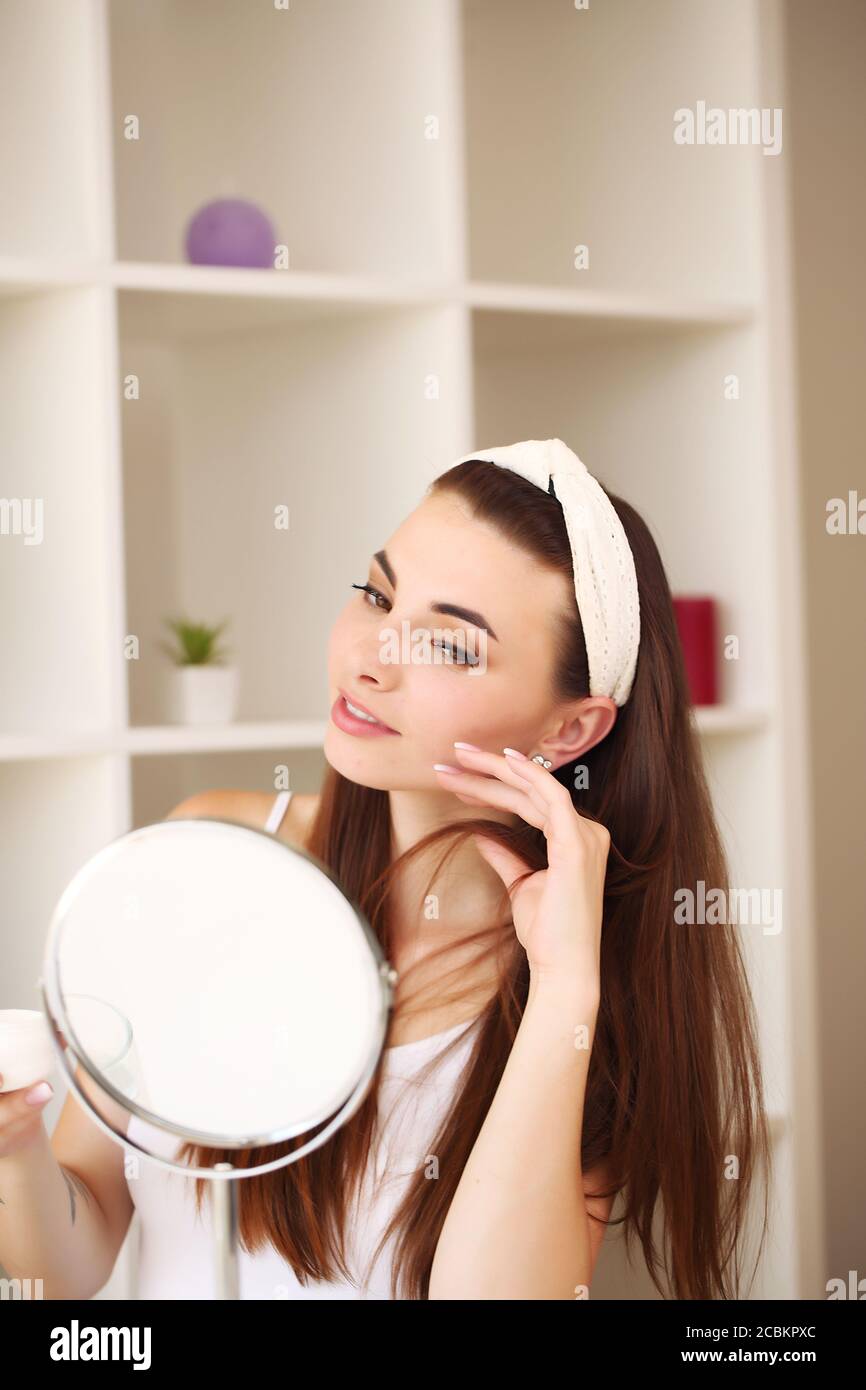 happy young woman putting face cream to do morning healthy skin care ...
