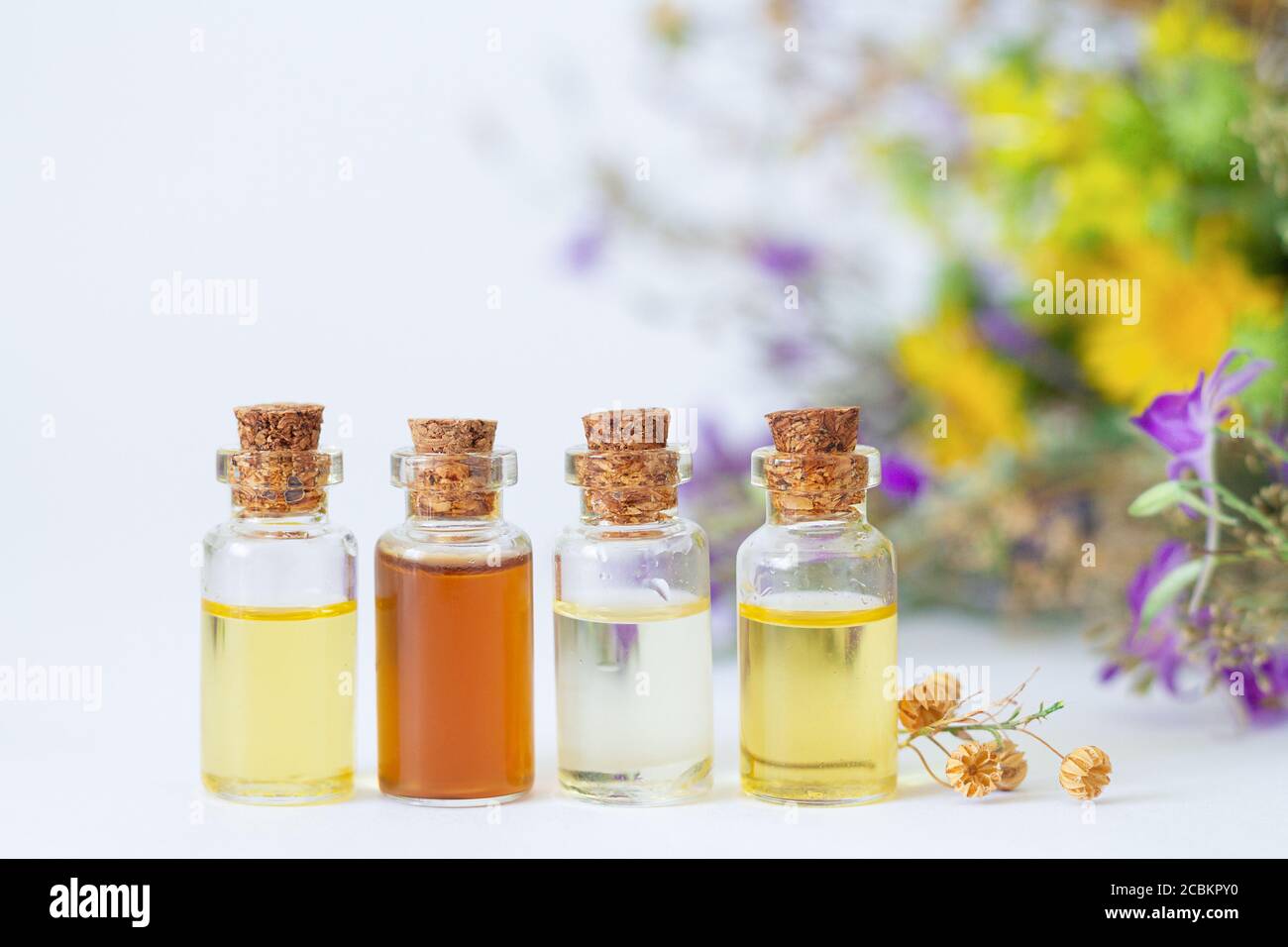 Bottles with organic essential aroma oils on wildflowers and dried ...