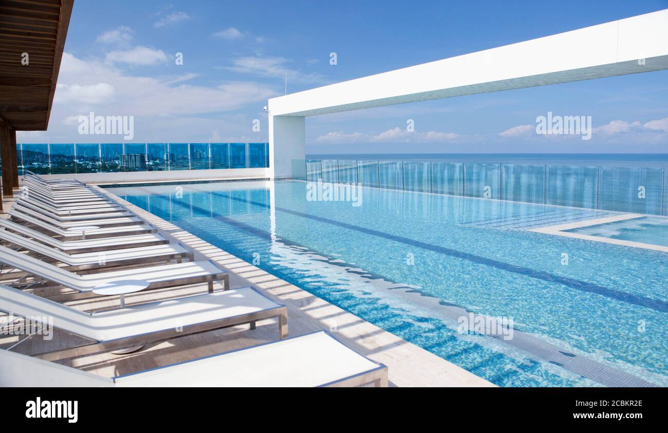 Lawn chairs by modern infinity pool Stock Photo - Alamy