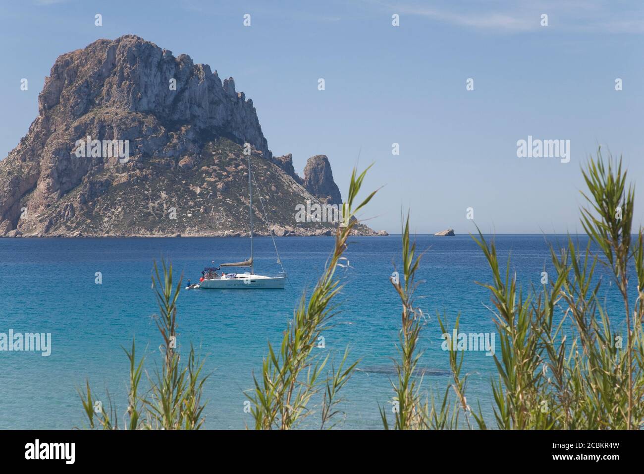 Boat floating in ocean by rock formation Stock Photo - Alamy