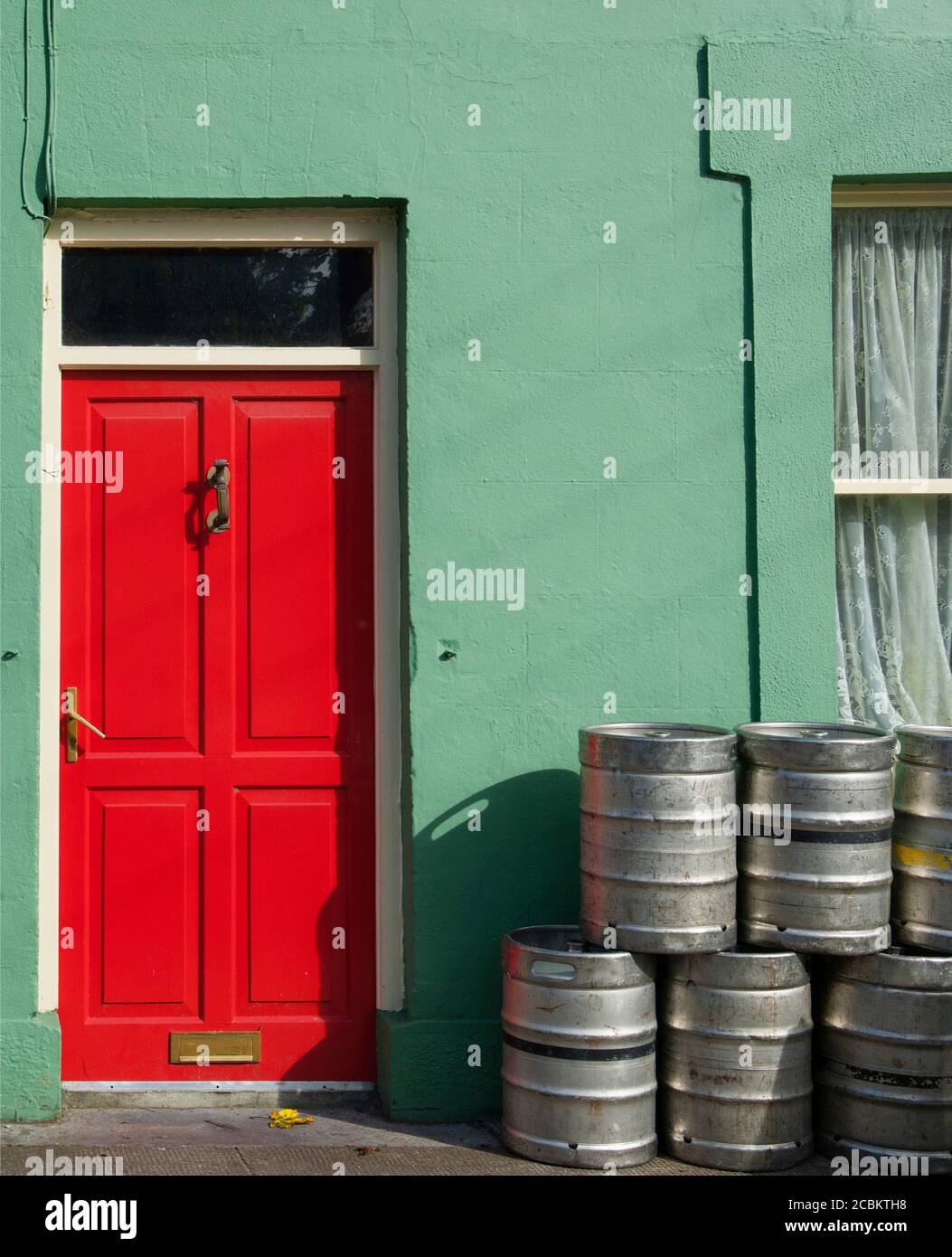 Stacked beer kegs outside house with red door, Ireland Stock Photo - Alamy