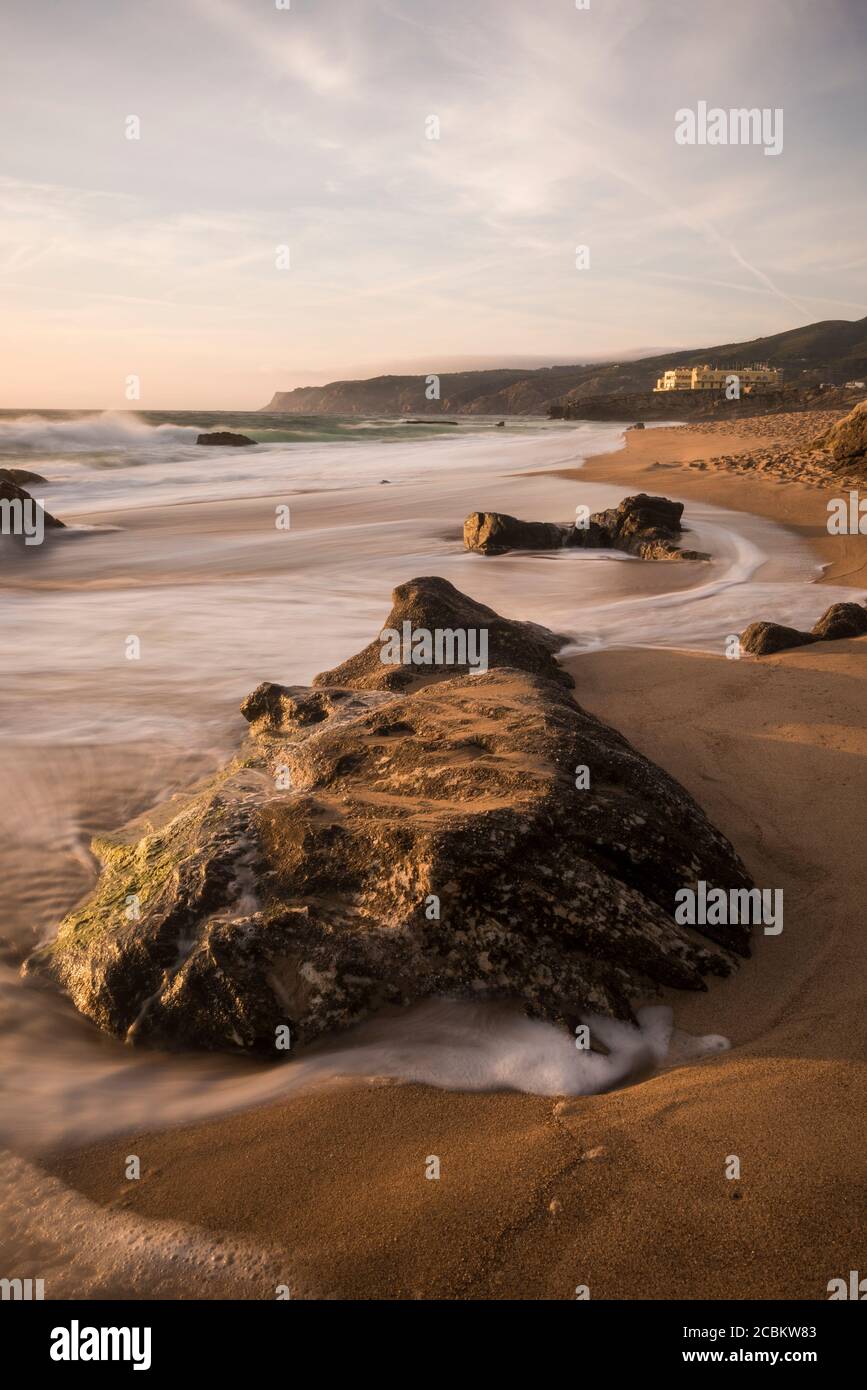 View down beach of tidal waves lapping rocks, Praia do Guincho, Lisbon ...