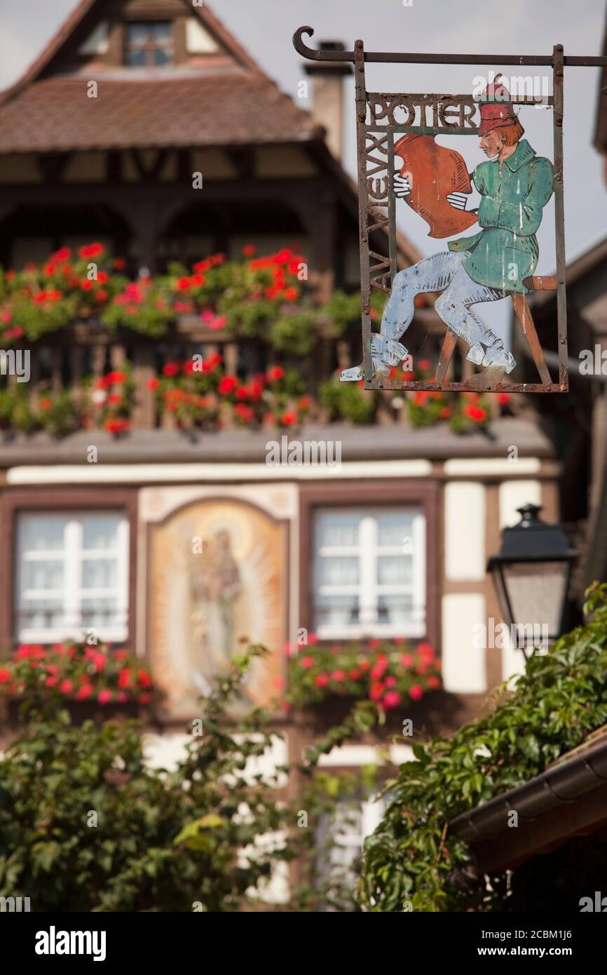 Business signage and medieval house in background, Kaysersberg, Alsace ...
