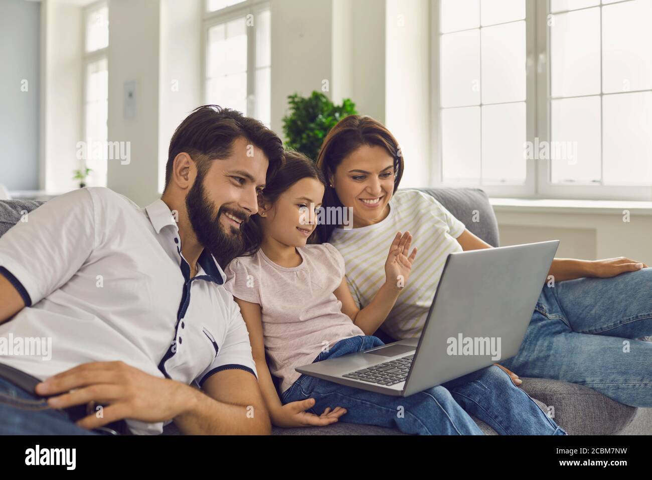 Parents and child online. Beautiful family uses laptop watching video ...