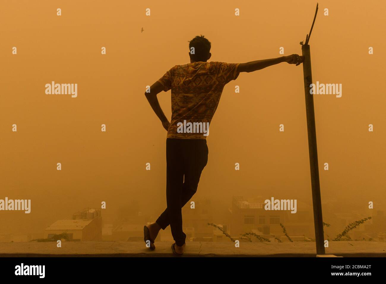 adult man leaning against the pole in the middle of the sand storm, man ...