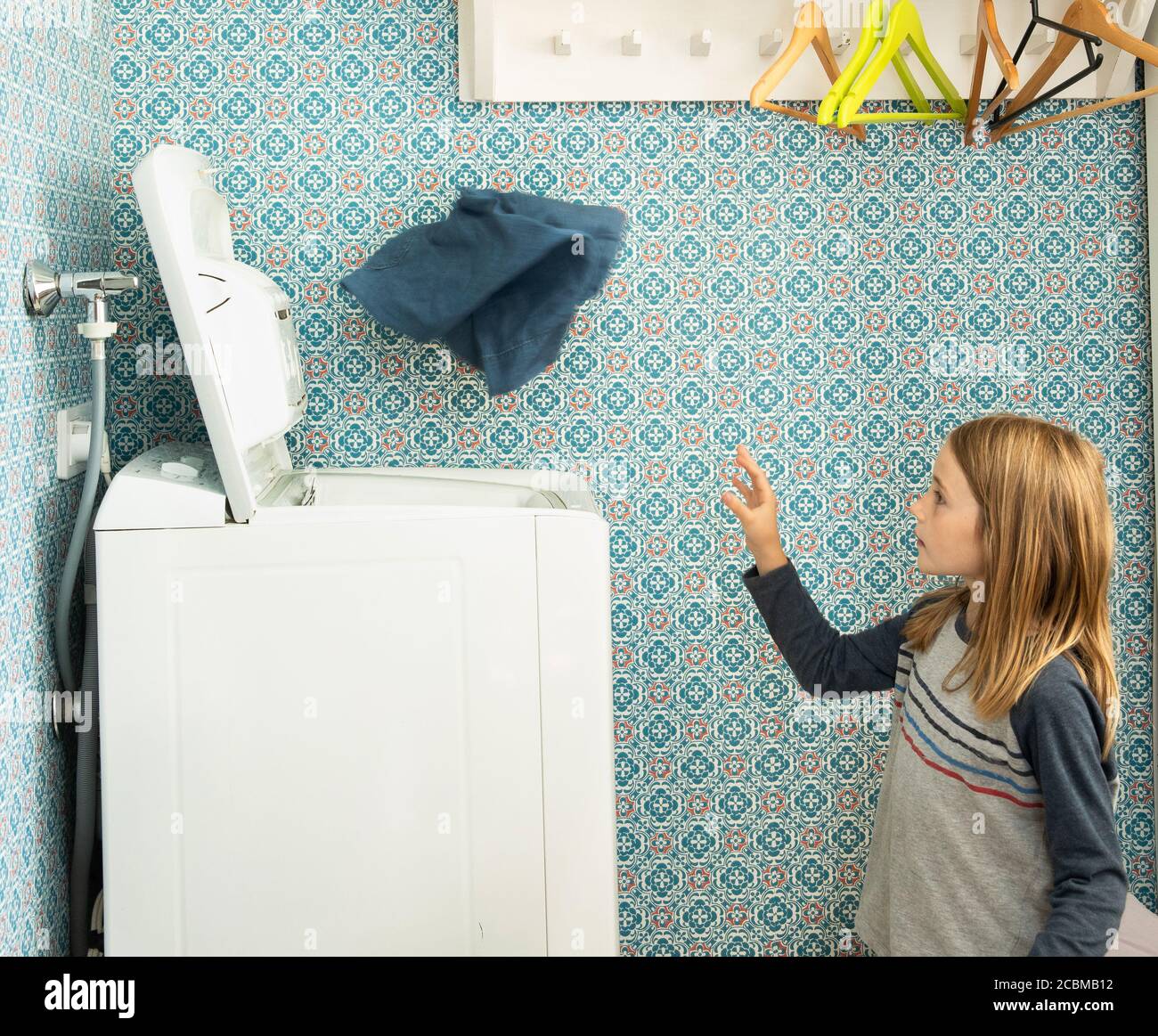 Little girl putting laundry into washing machine at home. Photography ...