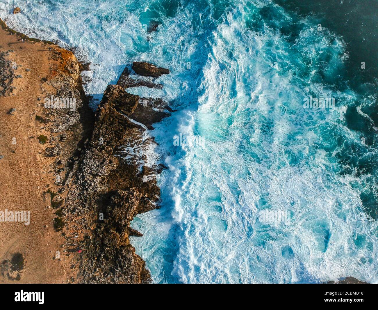 Aerial top view of sea waves hitting rocks on the beach with turquoise ...