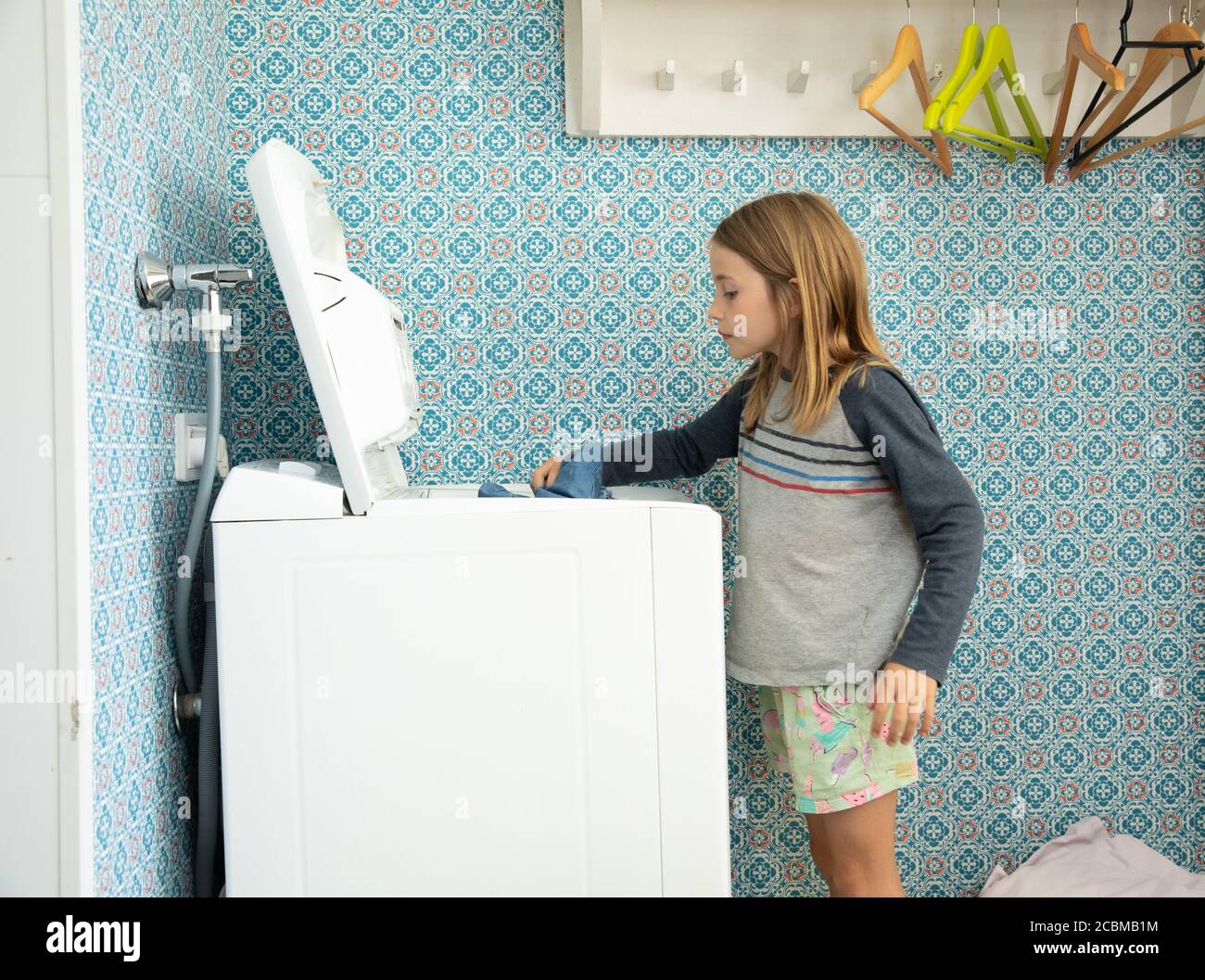 Little girl putting laundry into washing machine at home. Photography ...