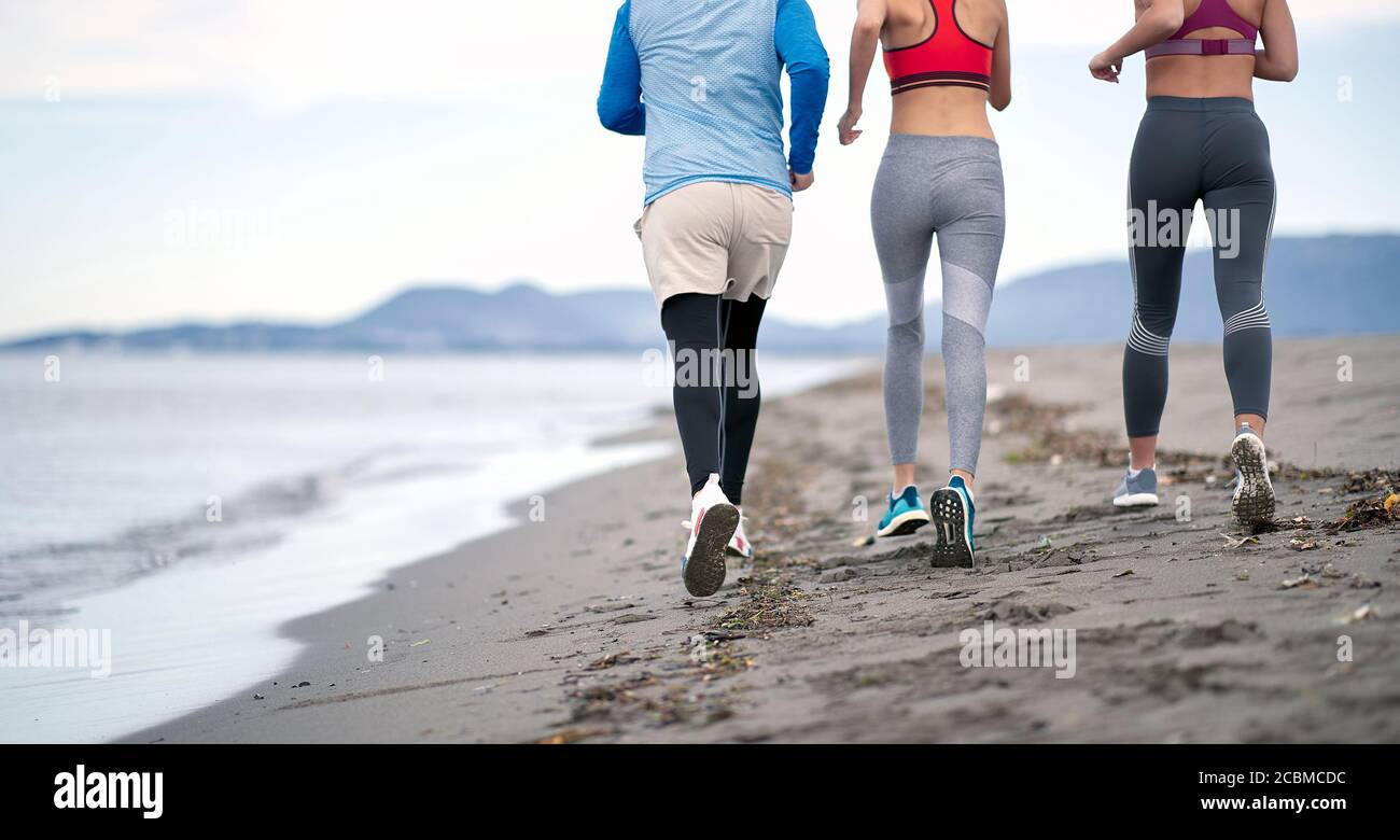 Group of three people jogging together on the beach Stock Photo - Alamy