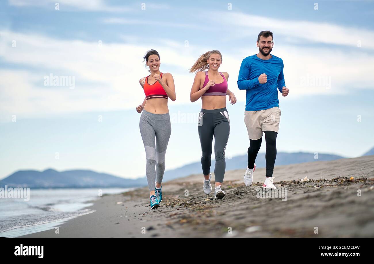 Group of people jogging together on the beach Stock Photo - Alamy