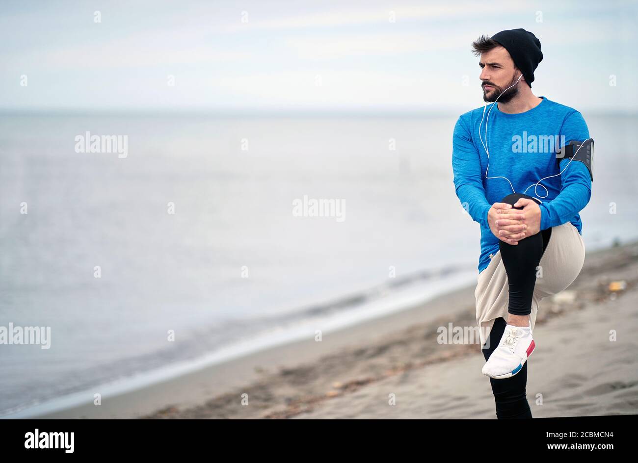 Man stretching alone on the beach; Active lifestyle concept Stock Photo ...