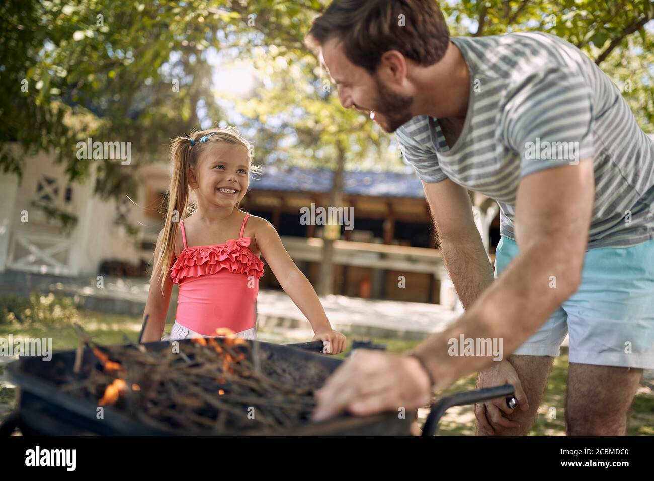 Father with his smiling daughter prepare fire for family barbeque Stock ...