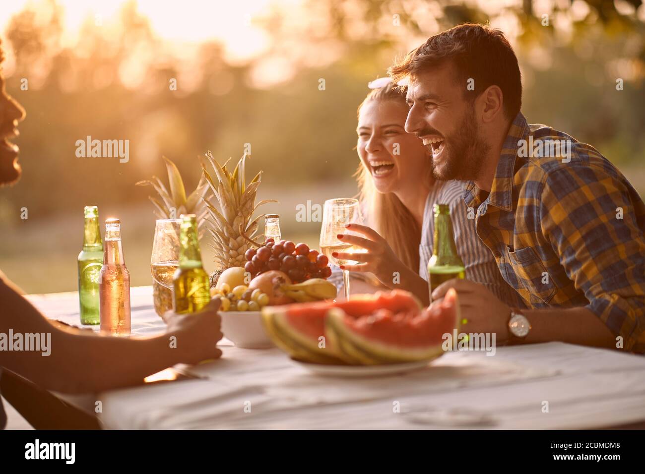 Multi-ethnic smiling young friends drinking at dinner party Stock Photo ...