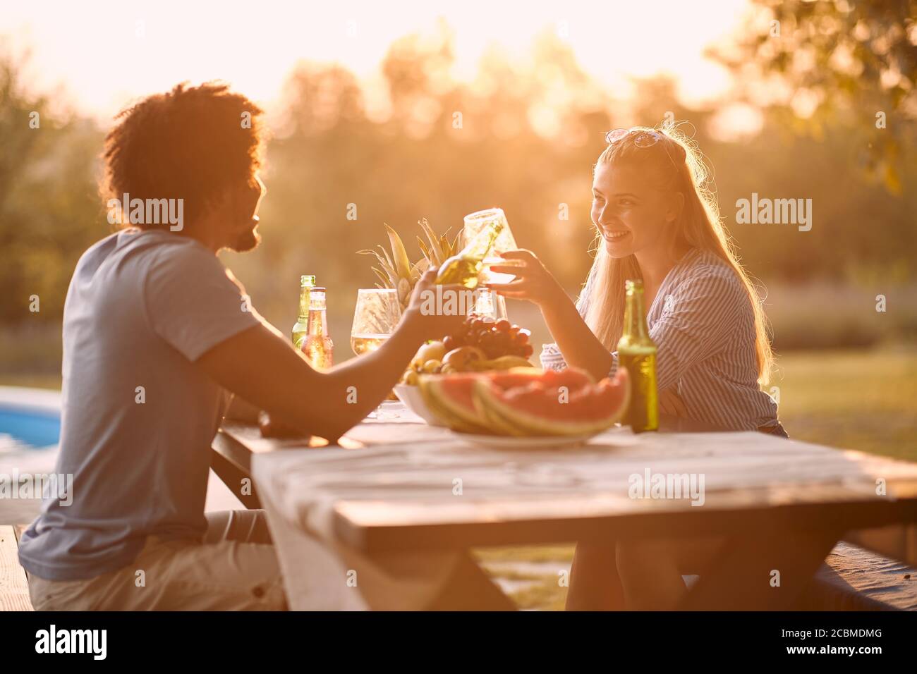Multi-ethnic cheerful young couple drinking at dinner party Stock Photo ...