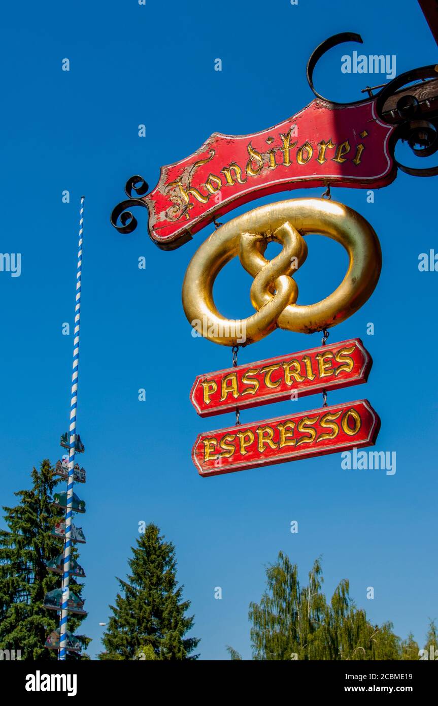 A pretzel sign in front of a bakery with the background of a Bavarian ...